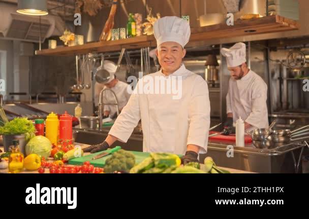 Portrait of professional male Asian cook standing in kitchen of ...