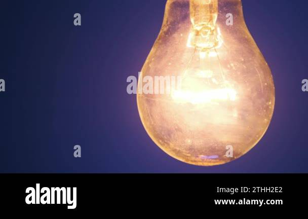 Incandescent lamp glows and flickers on dark blue background. Edison ...
