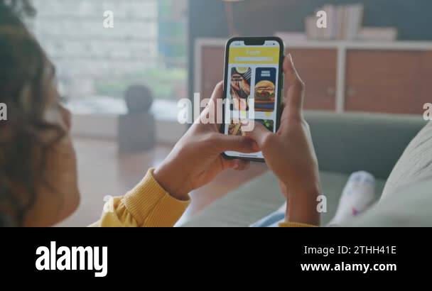 Woman on sofa looking at her cellphone. Woman searching what meal buy ...