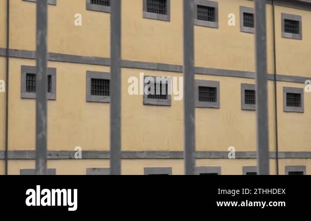 Prison building wall with barred windows of prison cells behind an iron ...