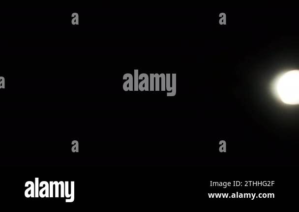 The light of a bright flashlight directed at the camera moves from side ...