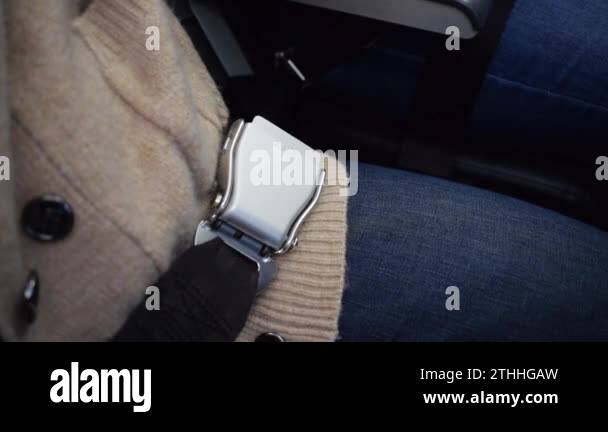 Female passenger undoing and opening seatbelt in commercial airplane ...