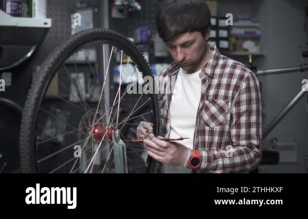 Working alignment of rim and spokes of bicycle wheel on wheel stand in bike repair shop. Bike ...