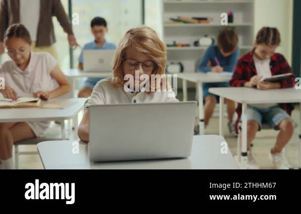 School boy using the computer sitting doing homework in the class ...