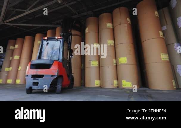 The forklift is carrying a large roll of paper. A forklift is carrying ...