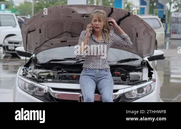 Unhappy Asian female car owner sitting on the front of her broken down ...