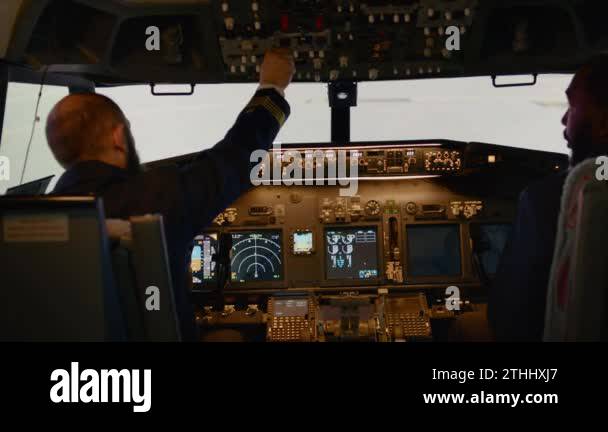 Diverse team of airliners turning on switch and buttons in cockpit ...