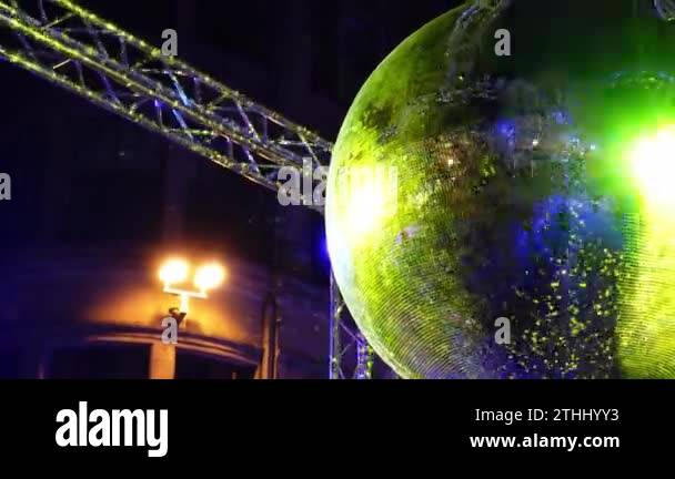 Disco Ball in the street rotates and reflects blue, yellow and green ...