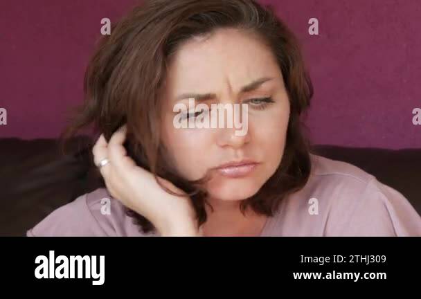 A young beautiful woman is sitting with her face propped up with her ...