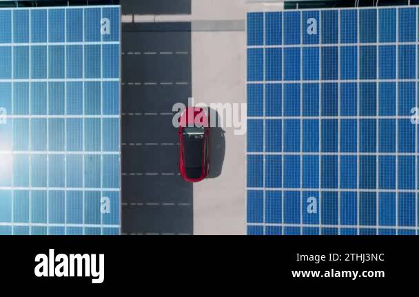 Overhead shot of red electric car driving by charging station. Electric ...