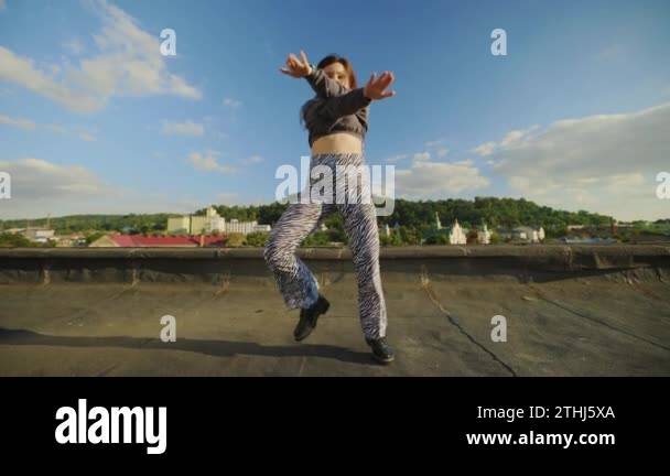 Cool young talented hip-hop girl dancing on the roof floor staring at camera performing amazing ...