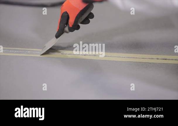 The builder covers the joint seam with sealant. Construction worker ...