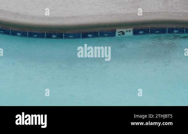 Rain drops falling on water surface of blue swimming pool, rainy day in ...