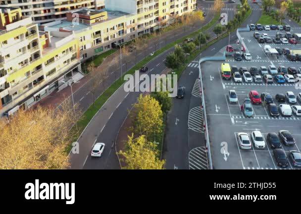 Cars leaving and entering parking space past big apartment building ...