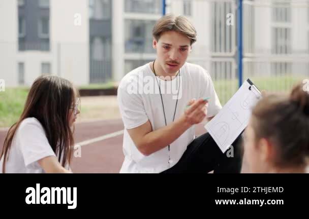 Sporty coach explaining game strategy to primary school children in ...