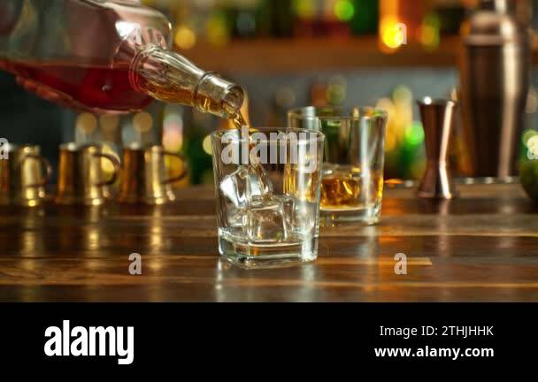 Detail of whisky bottle, pouring shot into glass, super slow motion ...