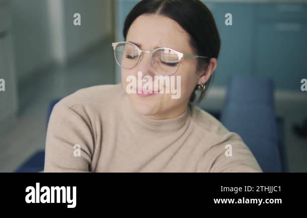 Young brunette woman taking off big eyeglasses and rubbing sore eyes ...