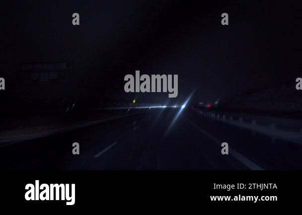 Blurred lights of streetlights and traffic lights. A car moves along an ...