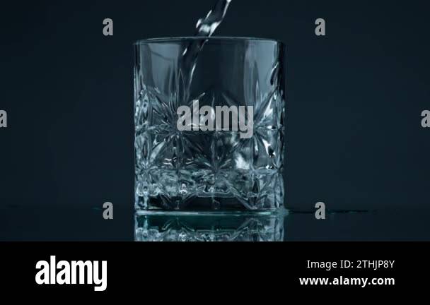 Pouring water crystal glass at dark background closeup. Liquid stream ...