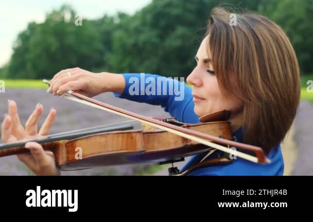 Middle aged woman in blue dress playing violin in lavender field on ...