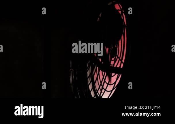 Slow-motion close-up footage of a rotating fan bladder in a dark red ...