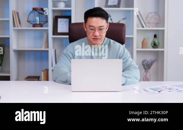 Chinese charismatic businessman is working in an office, typing on his ...