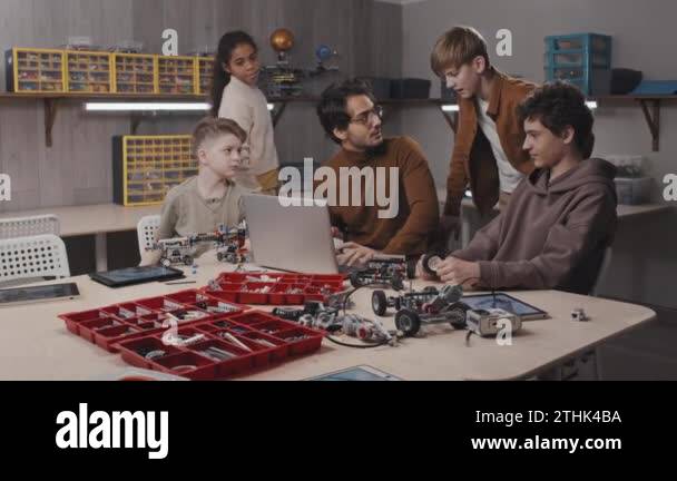 Young Middle Eastern teacher of Robotics explaining his students how to ...