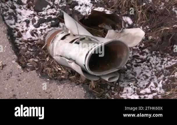 The remains of a rocket artillery shell stick out of the ground. Metal ...