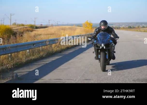 Young man riding on modern sport motorbike at autumn highway ...