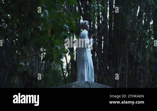 A Muslim man praying in the forest while standing on the big rock and ...