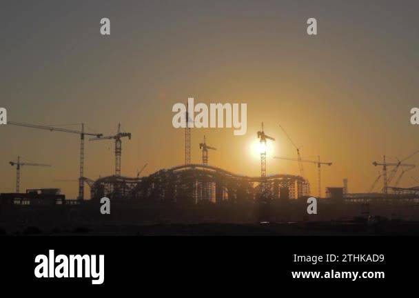 The rising sun appears from behind a silhouette building of the ...