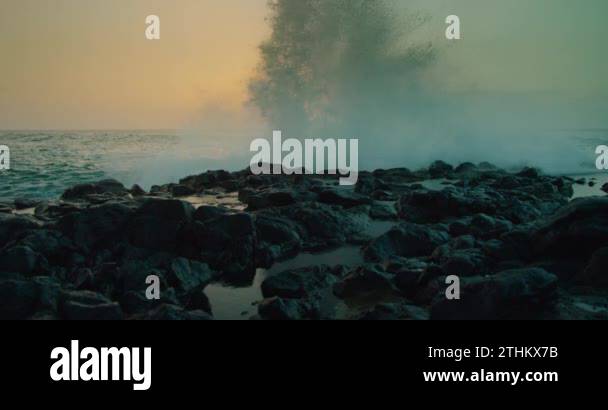 Ocean wave break crash spray splash on rocky shore against sunset sky ...