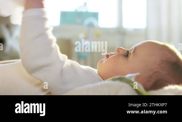 cute baby play with a stripe with a flower while his mother change the ...