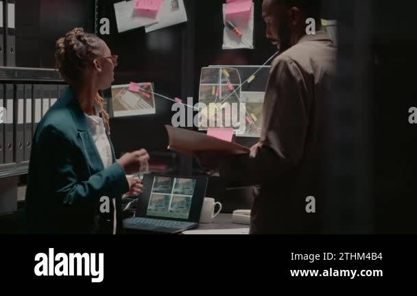 Detective partners analyzing criminal records in office, looking at ...