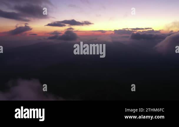 Low key aerial view evening flight over clouds and hills in the ...