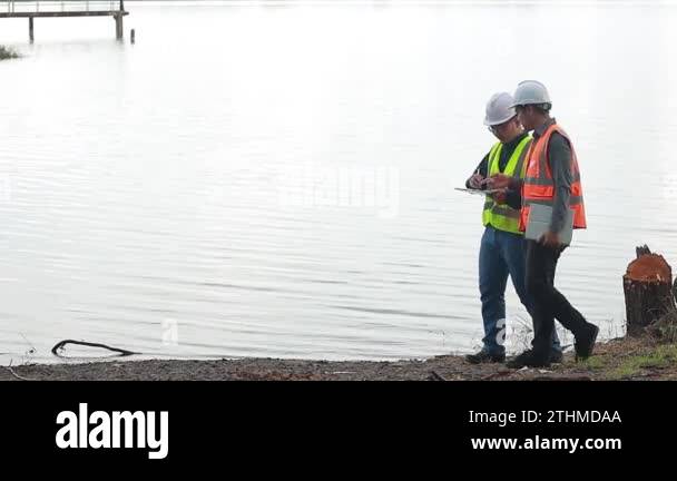 Environmental two engineers work at water source to check for contaminants in water sources and ...