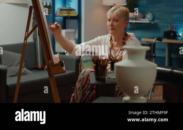 Senior artist with chronic impairment drawing vase design on canvas ...