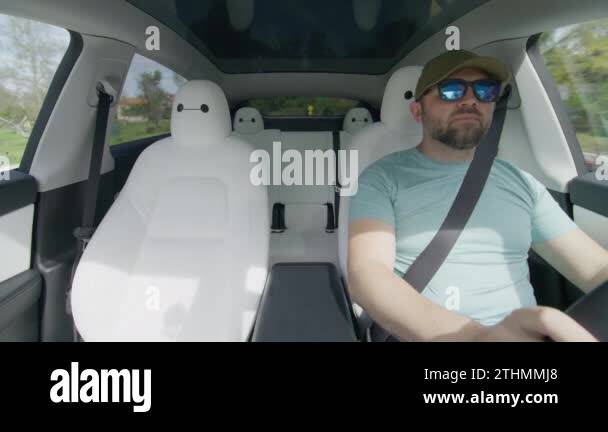 Mature male driver inside Tesla Model Y car using self drive autopilot ...