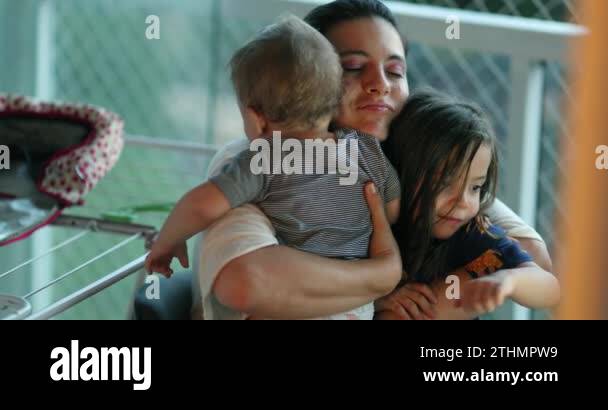 Mother hugging children baby and daughter in arms. Real life authentic ...