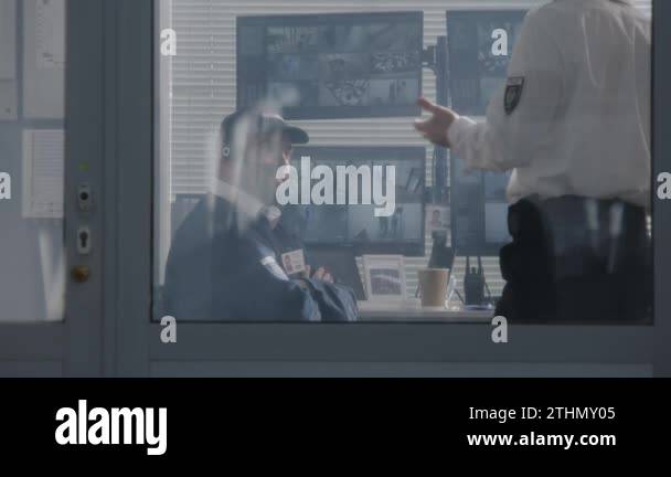 Security officers talk in surveillance room while monitoring CCTV ...
