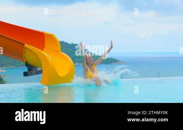 Woman in blue swimwear slides down a water slide at an aquapark resort ...
