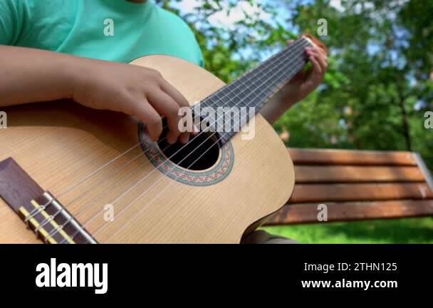 The hands of a young man fingering the strings of a classical guitar ...