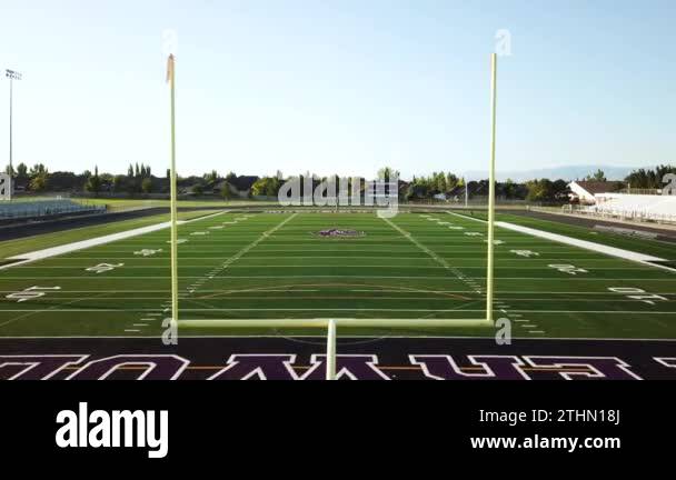 Drone Shot over an empty high school football field with a track going ...