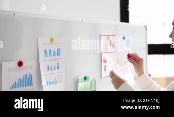 Intern student putting paper with infographic charts on whiteboard and ...