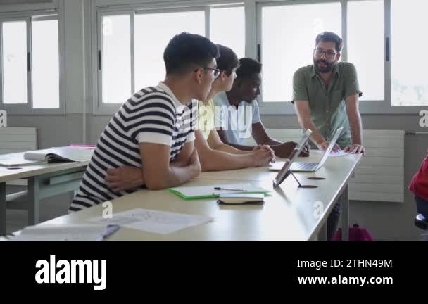 Young Professor helping multi ethnic male students in High School ...