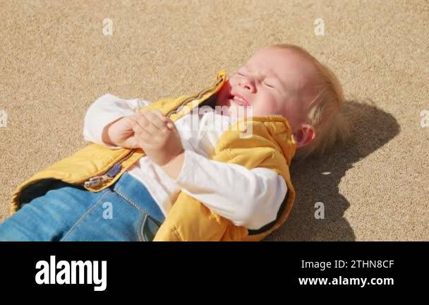 Little baby boy getting very upset lying on the ground and crying ...