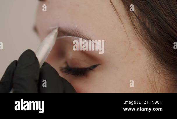 Master applies white markings to correct shape of eyebrows with a ...