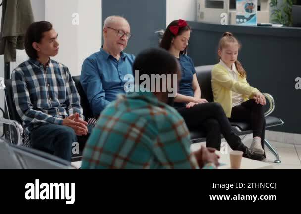 Different people waiting in row at hospital reception lobby to be ...