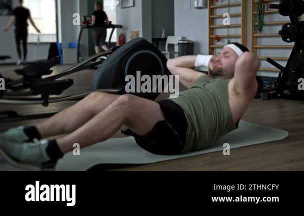 An overweight man is diligently pushing his abs while lying down on a ...