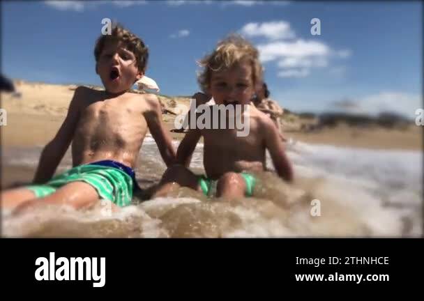 Kids playing at the beach with ocean waves. Real life authentic ...